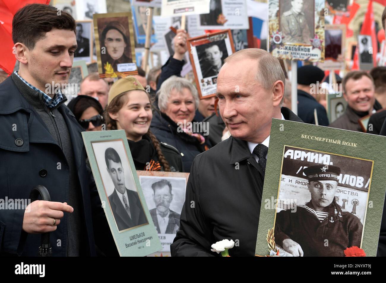Russian President Vladimir Putin, right, holds a portrait of his father ...