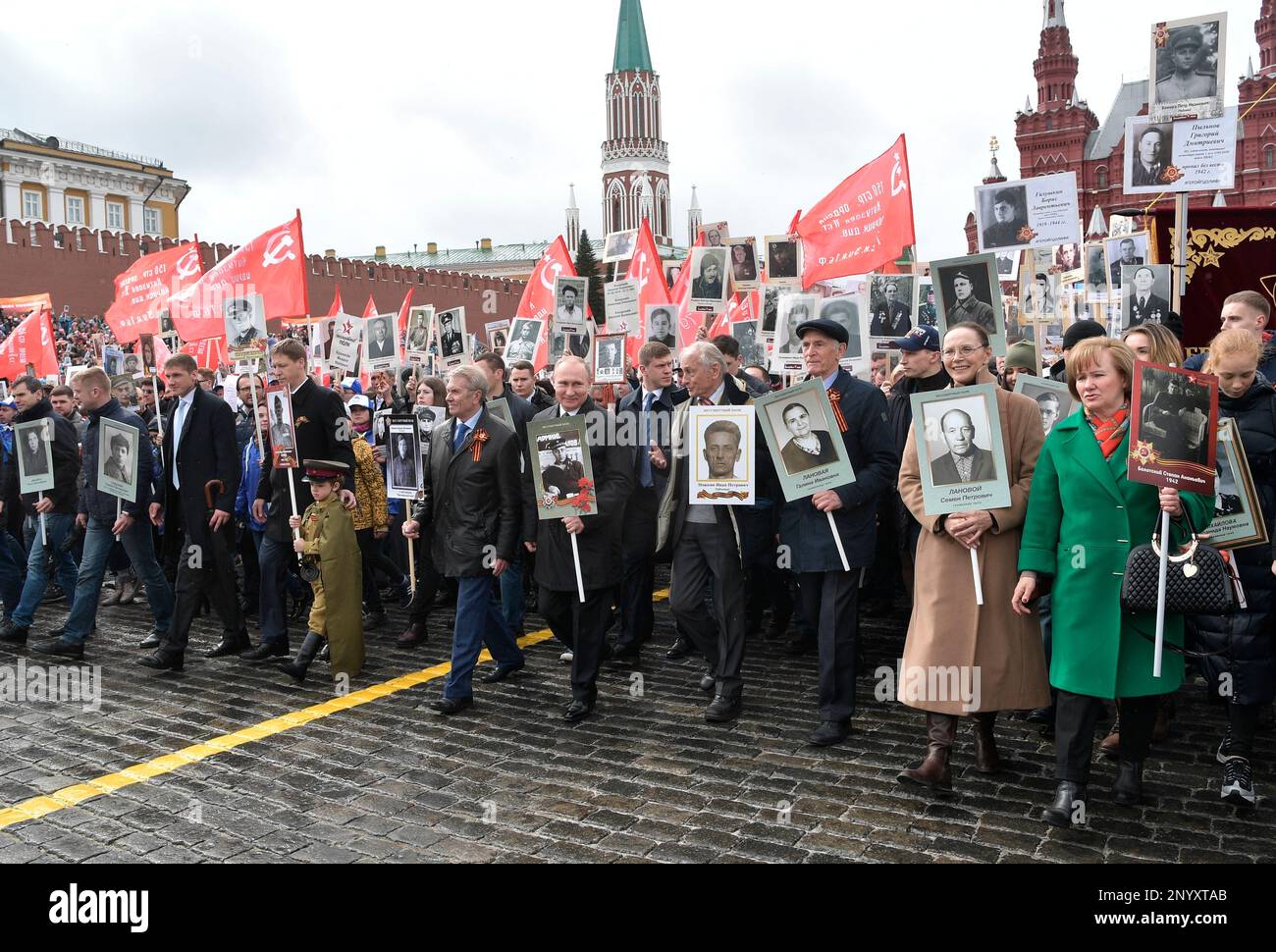 Russian President Vladimir Putin, center, holds a portrait of his ...