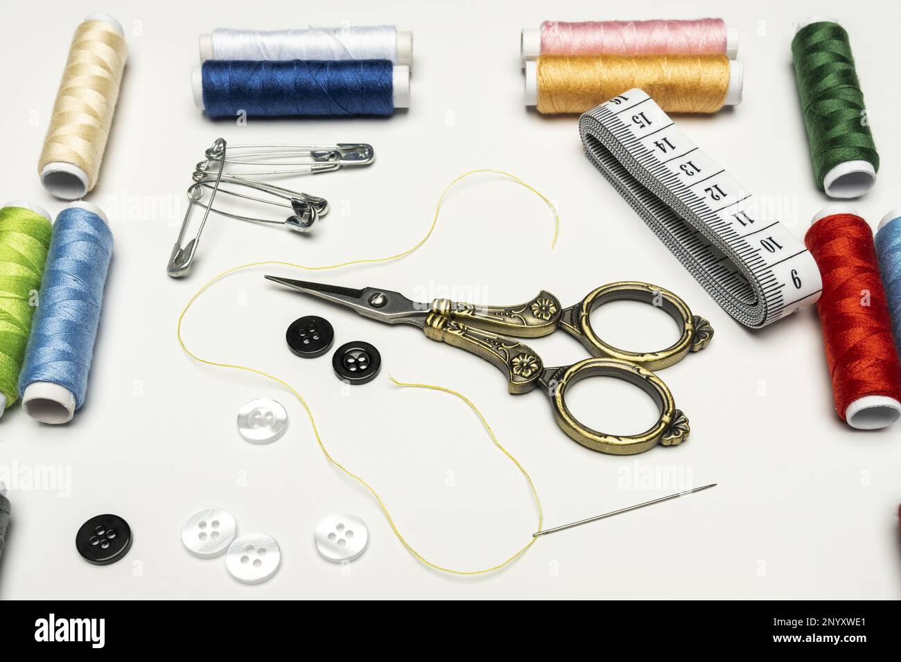 Still life with golden vintage sewing scissors on a white surface along ...