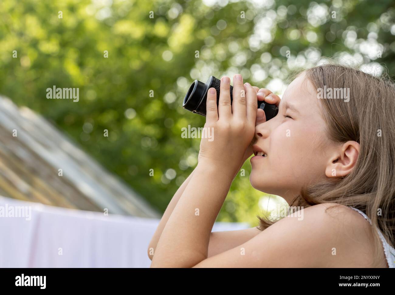 Elementary school age girl looking up into the sky through a magnifying ...