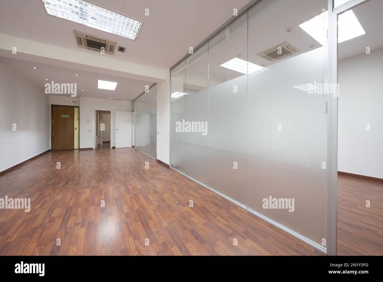 An empty office with dark wooden floors, technical ceilings and ...