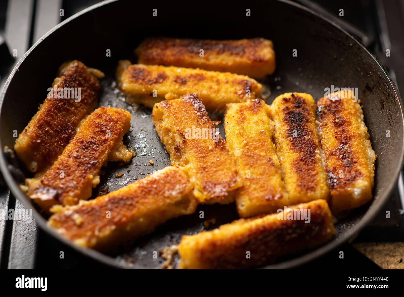 Fried fish sticks breaded in a frying pan. Preparation of frozen fish ...