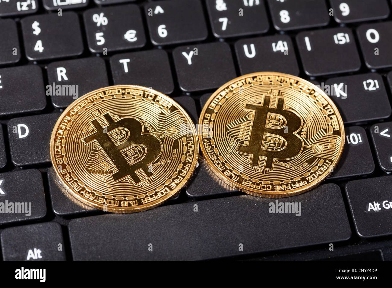 Two old dusty gold bitcoin coins, coin symbols laying on an old laptop ...