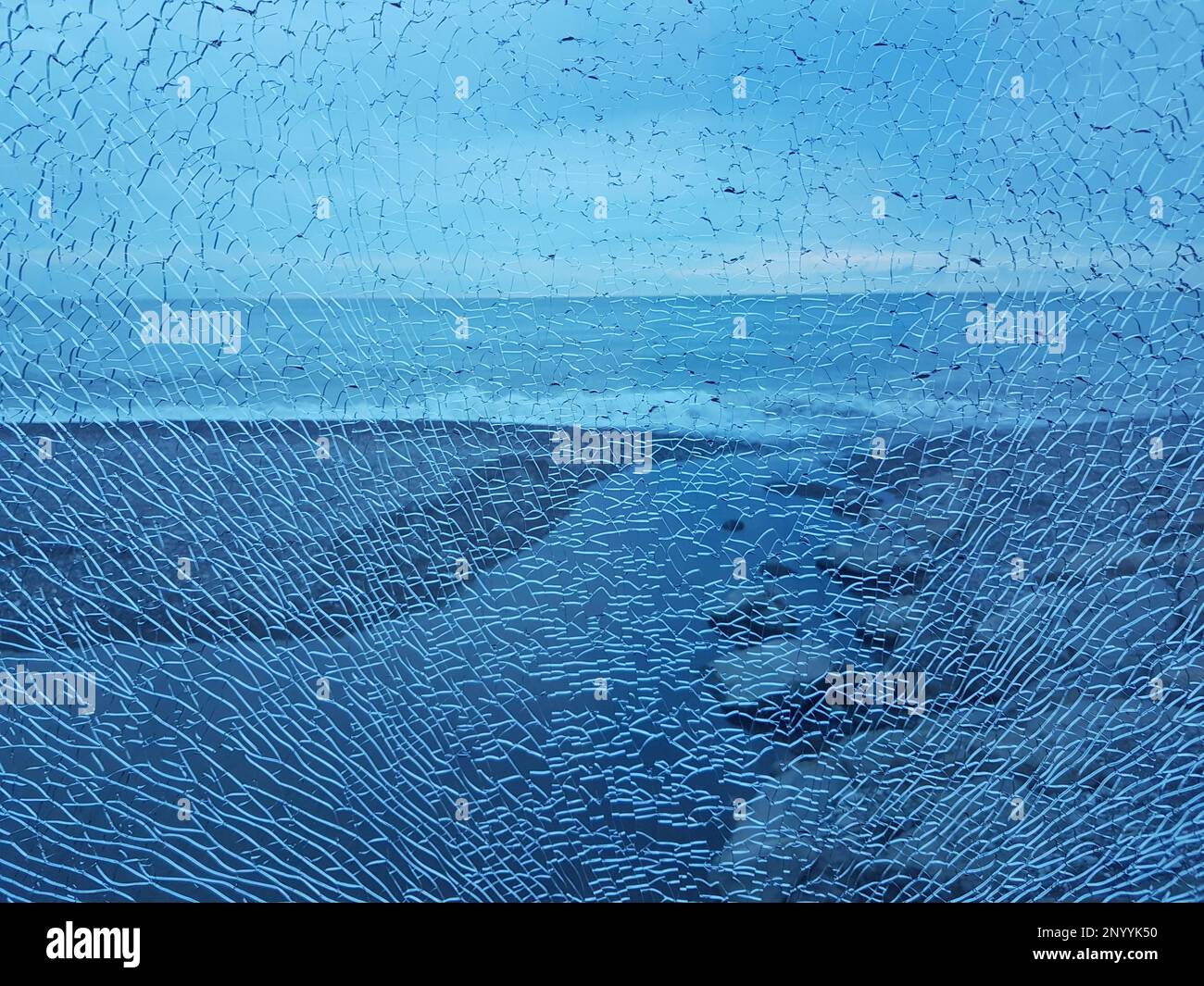 Abstract blue broken cracked glass window against seaside background ...