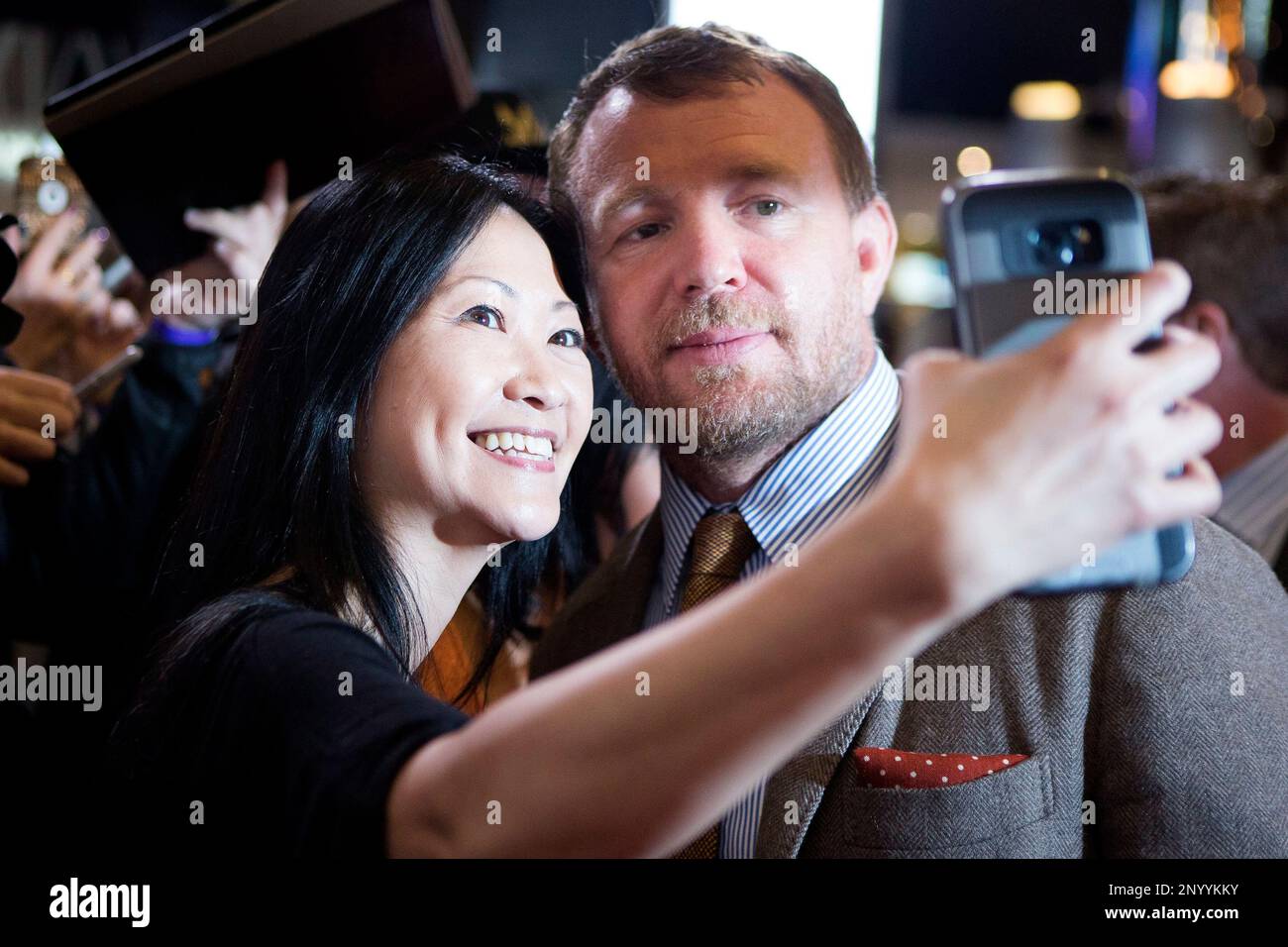 Director Guy Ritchie poses for a photo with a fan as he arrives on the ...