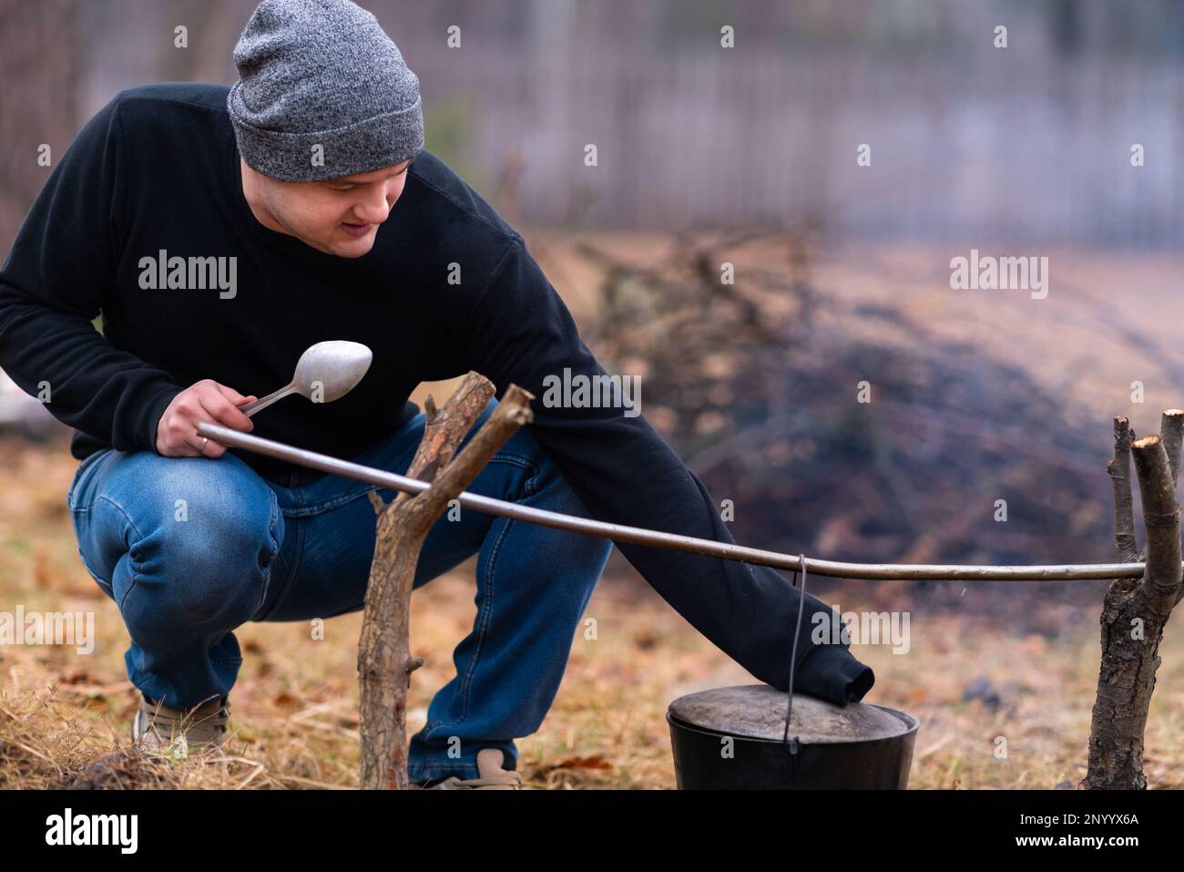 The guy holds a large spoon in one hand, and with the other he lifts ...