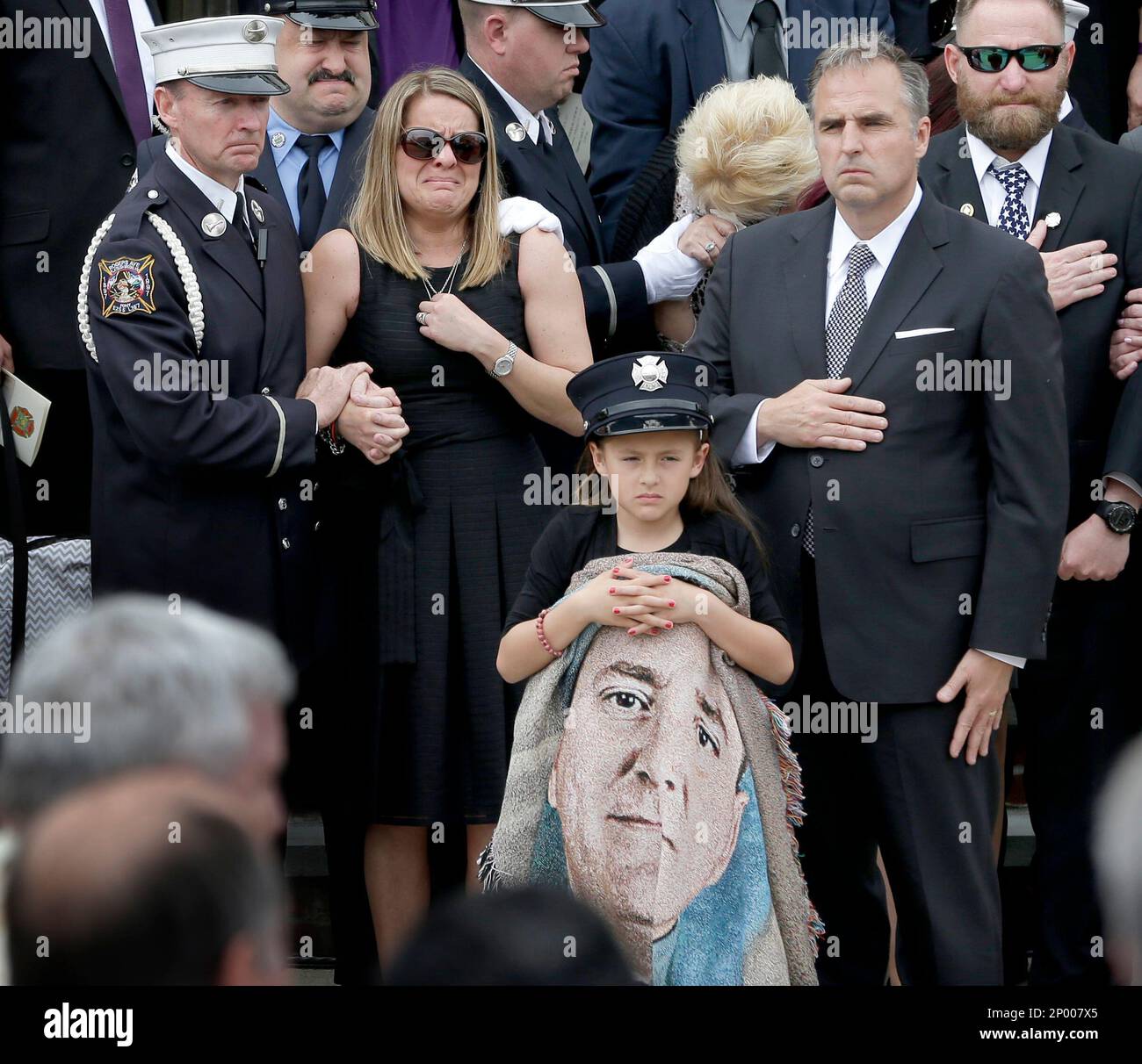 Isabella Tolley, 8, center, holding a blanket with a picture of her ...