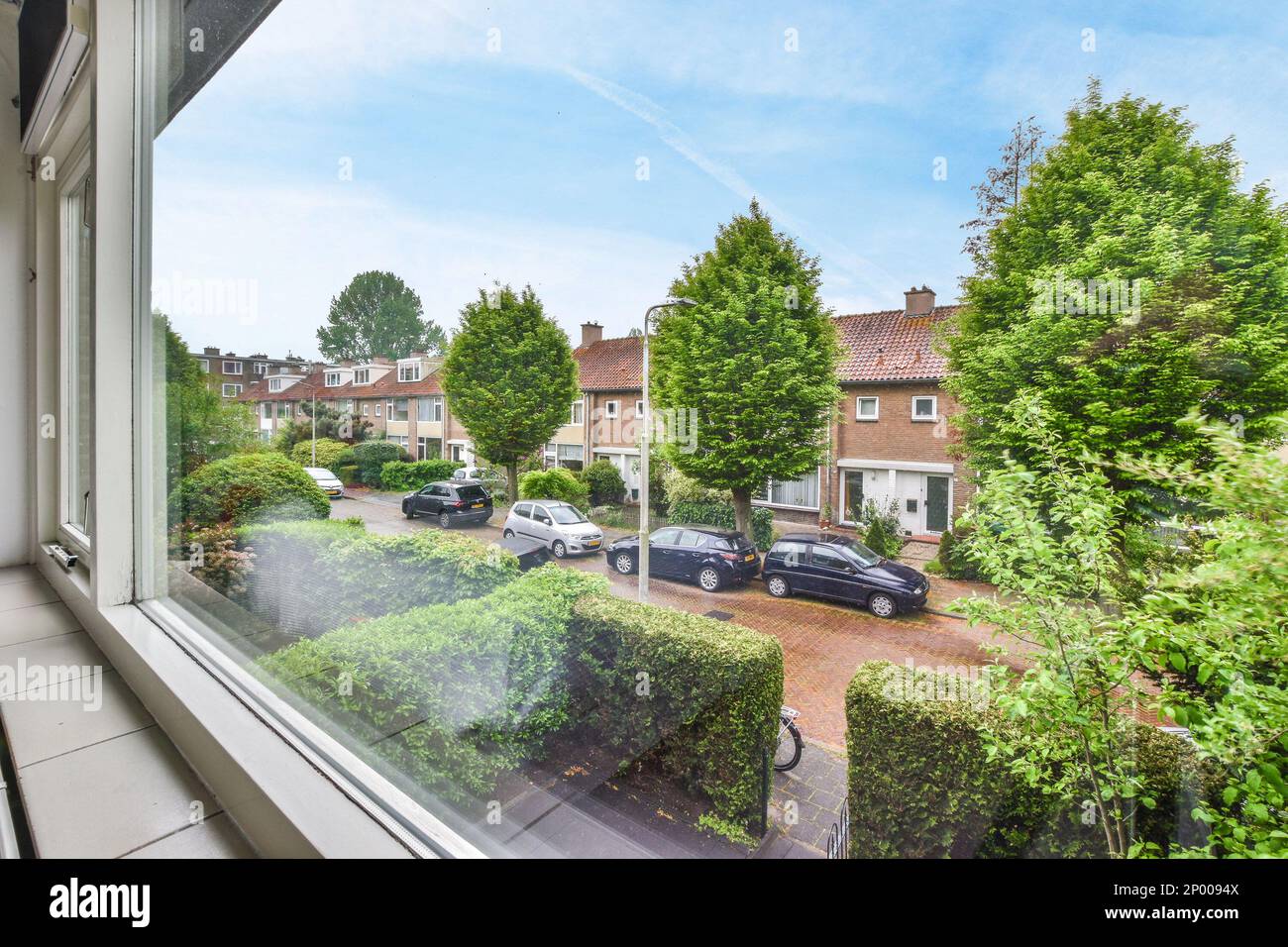 a view from the window of a house with cars parked on the street and ...