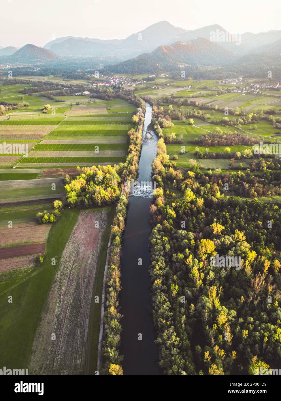 Vertical photo of a river running trough the country side with suburban ...