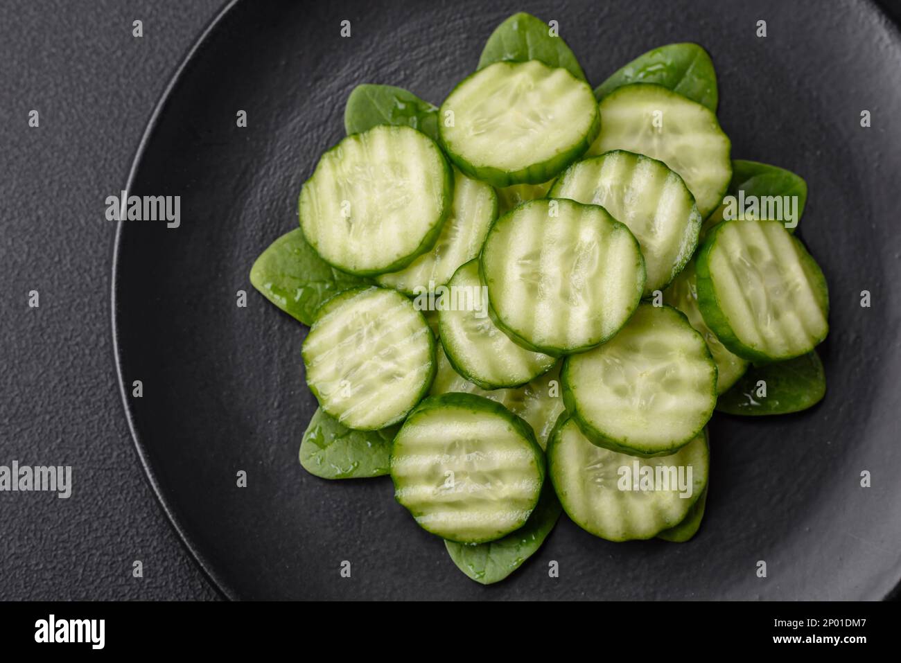 Delicious healthy raw cucumber sliced ??on a black ceramic plate on a ...