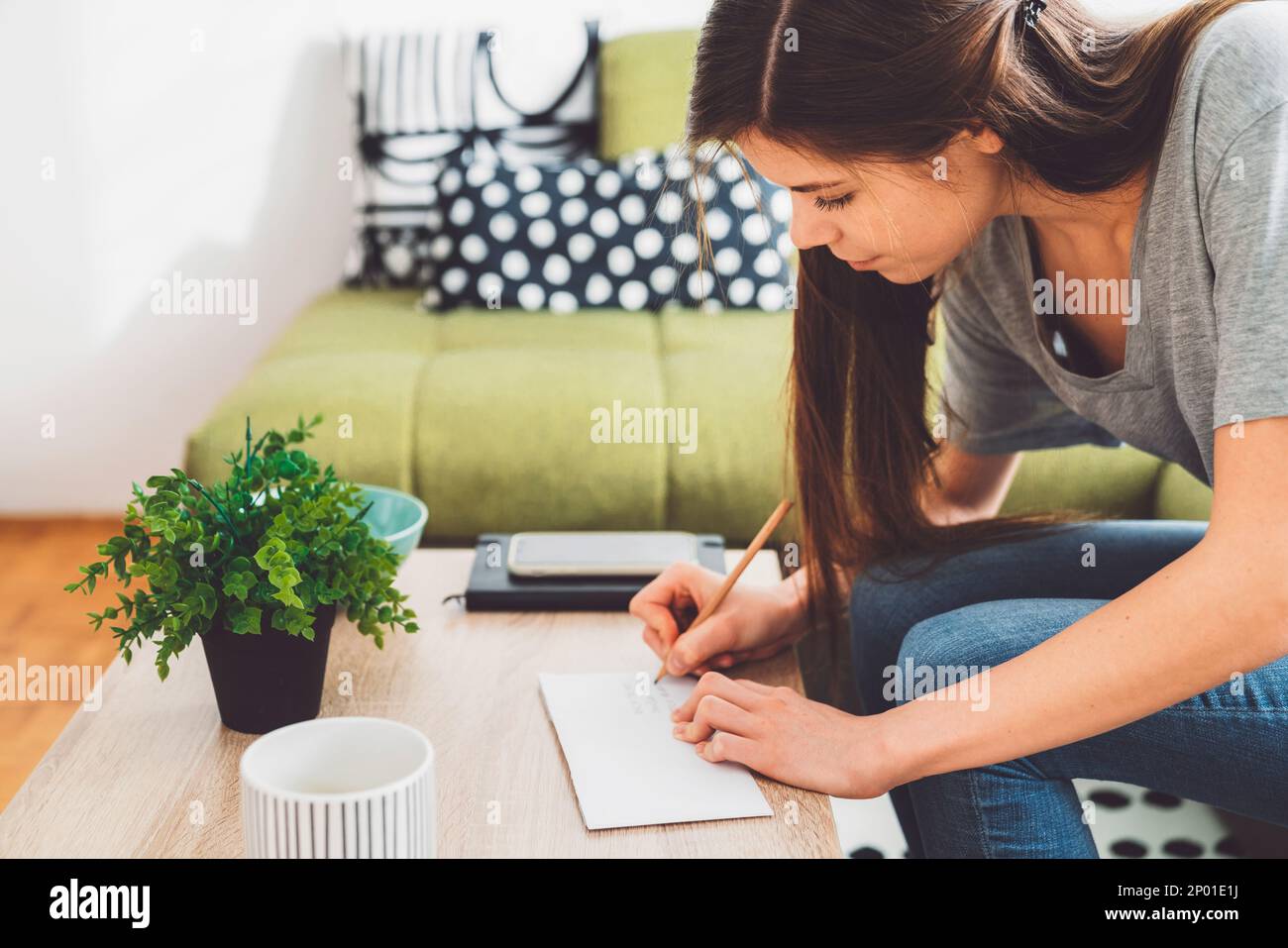 Young caucasian woman sending a letter, writing the address on it Stock ...
