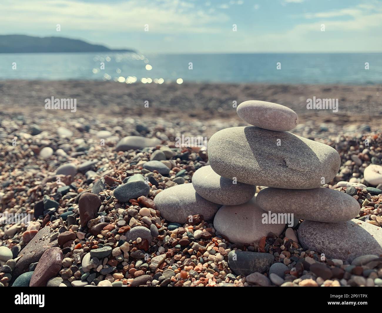 Small stone pyramid on the seashore coast close to the water. Mountains ...