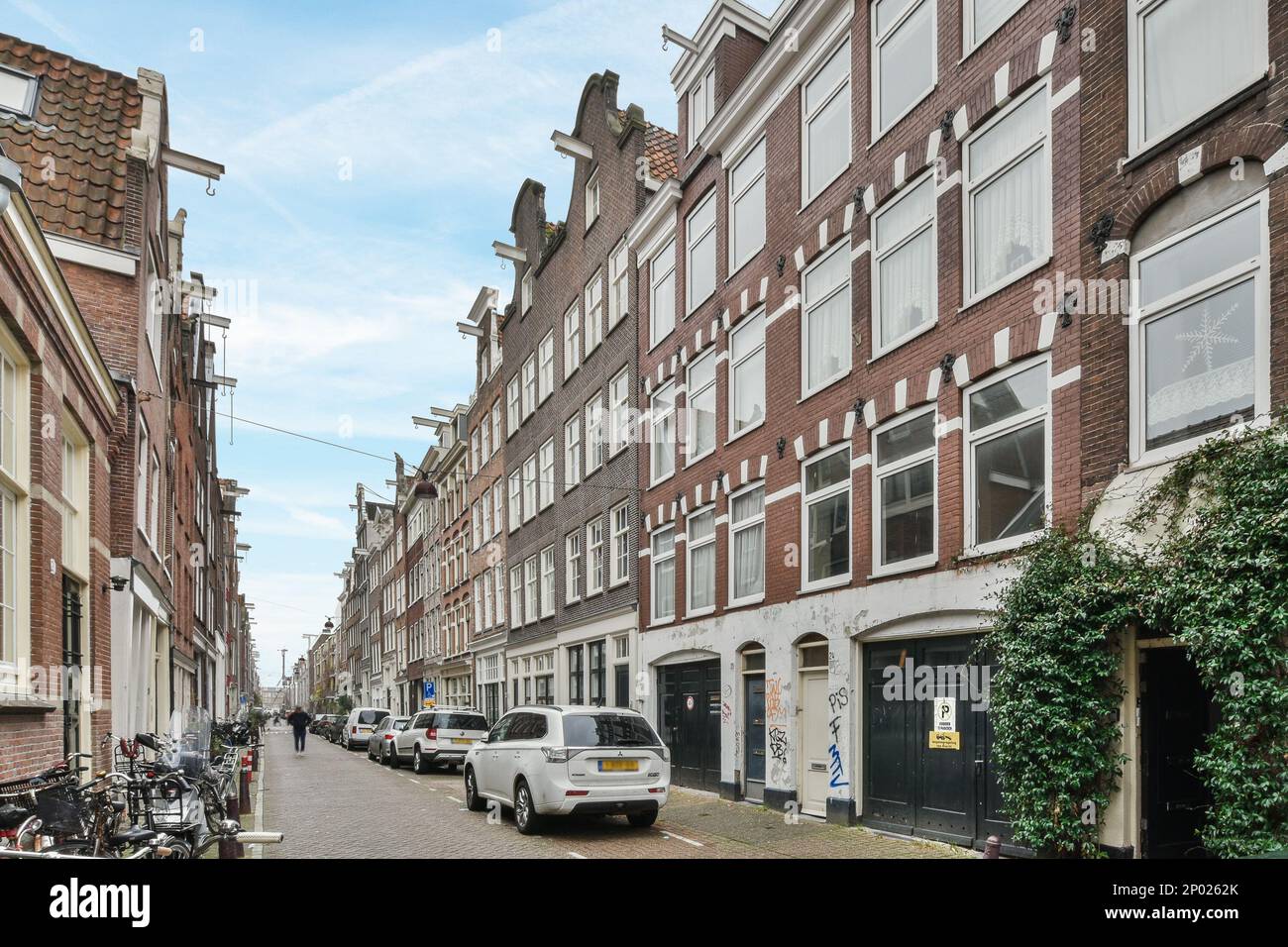 a street with cars parked on the side and people walking down the road ...