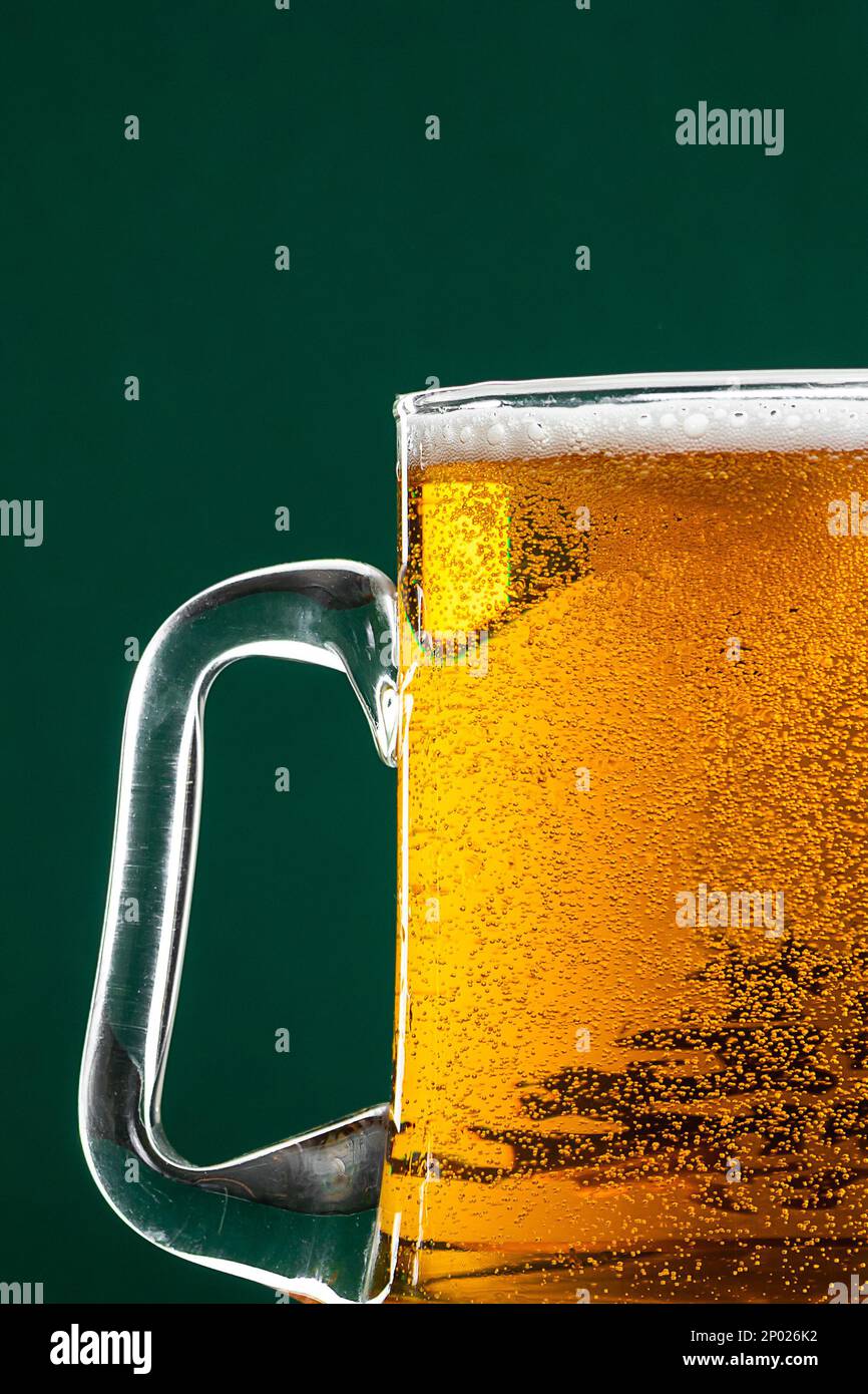 Mug of light beer with foam on green background. Traditional Irish ...
