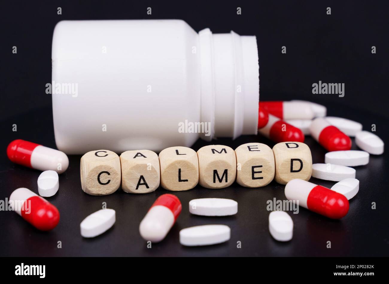 Medical concept. On a black background are red-white capsules, tablets ...