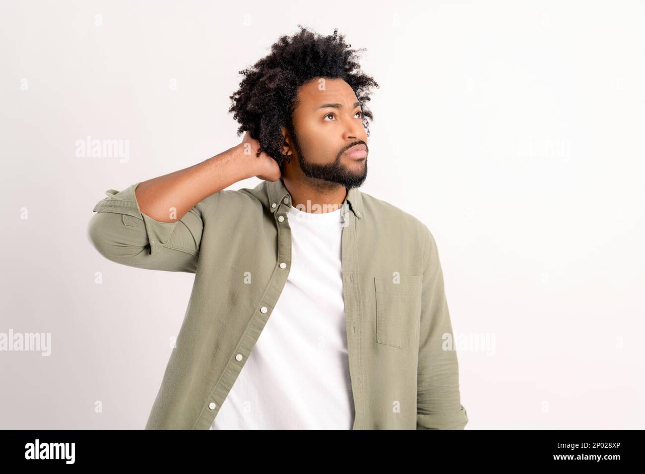 Puzzled African-American curly guy holding hand on the back of the head ...