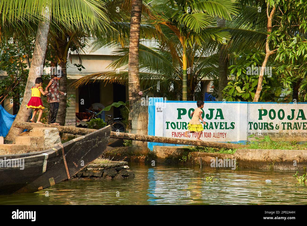 Children walking and running over a tree stump to cross the river in ...