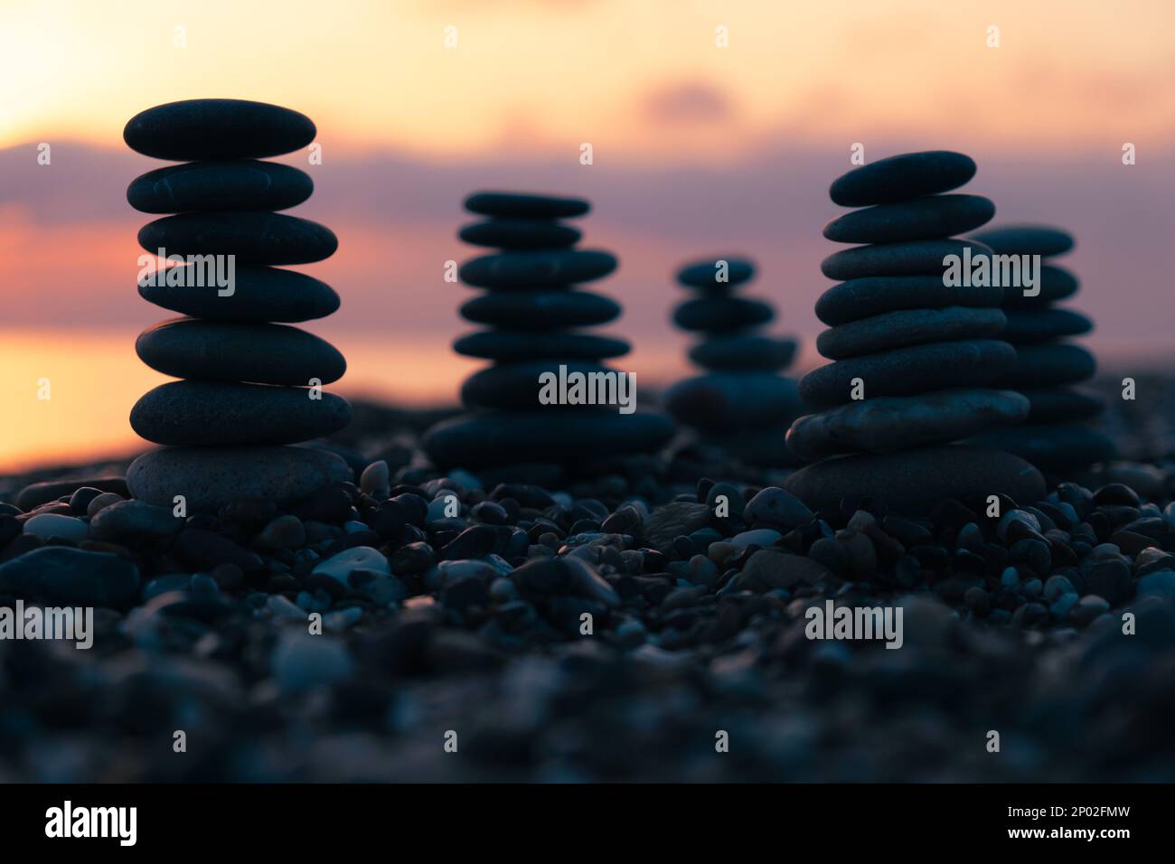 Balanced pebble pyramid silhouette on the beach on sunset with Sea on ...