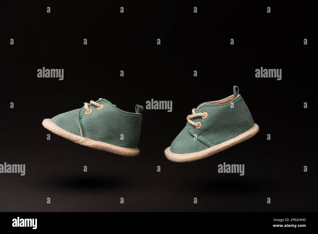 Flying shoes of newborn baby on black background. Childhood concept ...