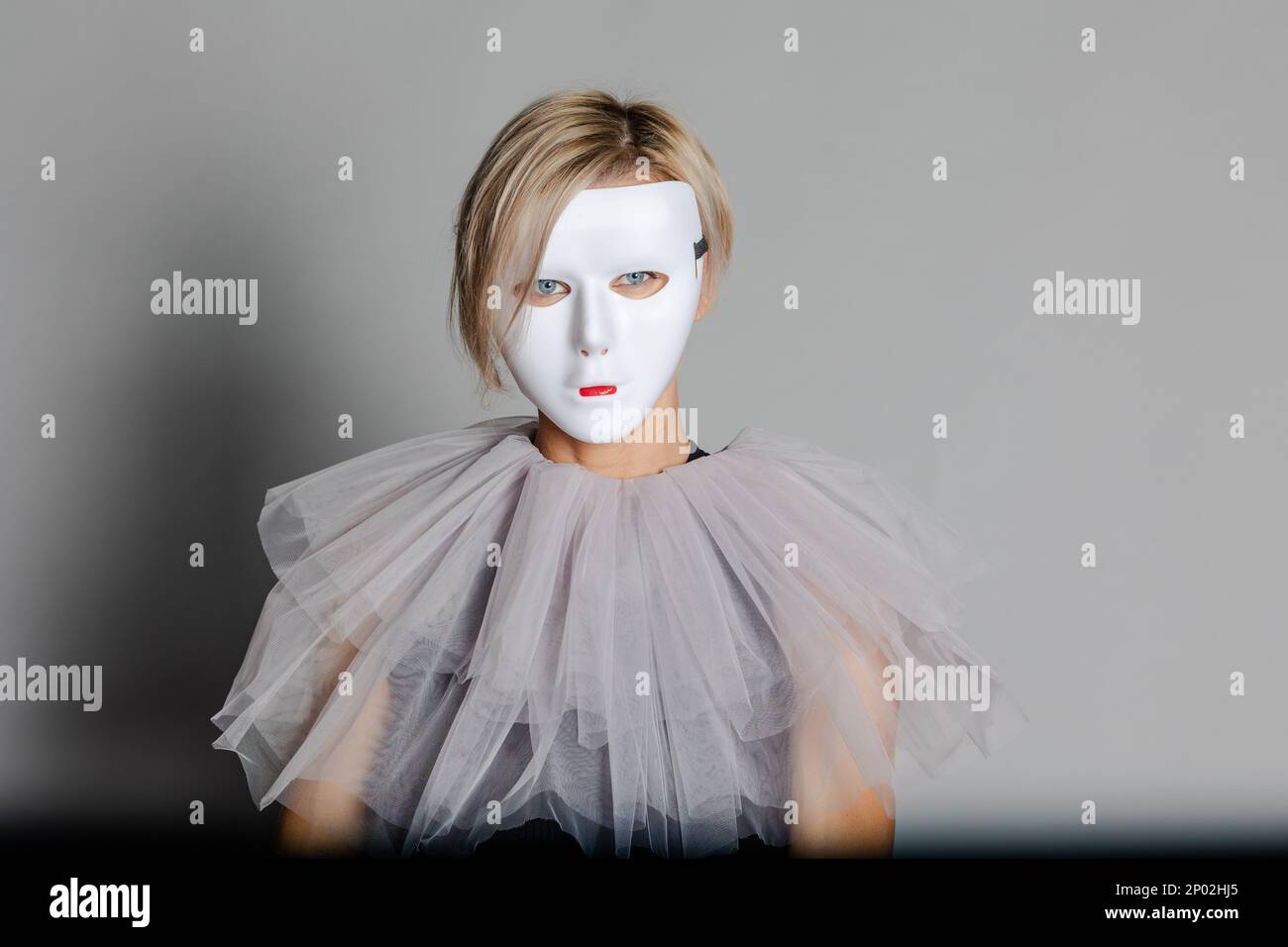 Face behind mask. Woman in white theater mask and harlequin collar on ...