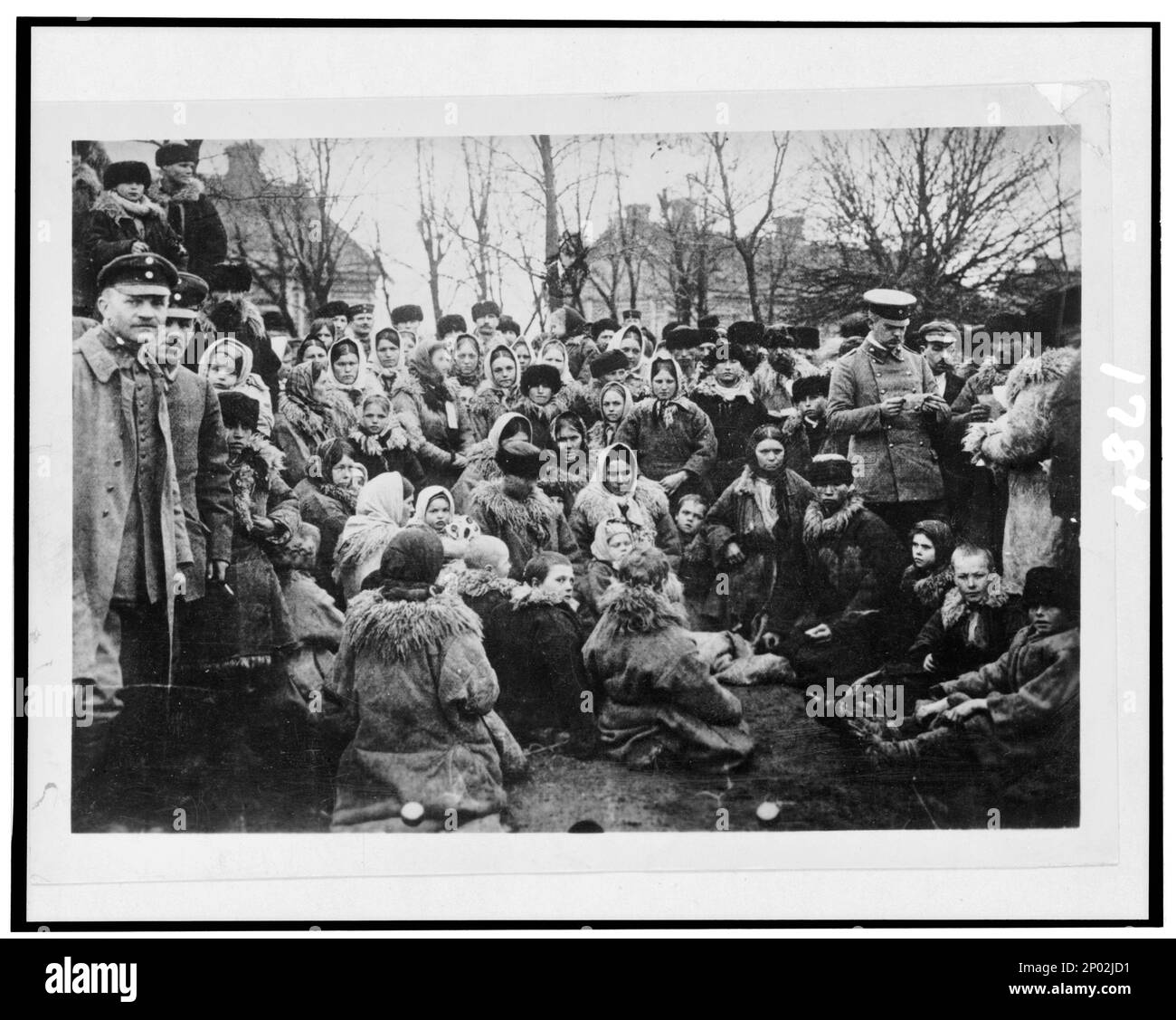 Crowd of refugees(?)--, possibly Jewish, and three officials outdoors ...