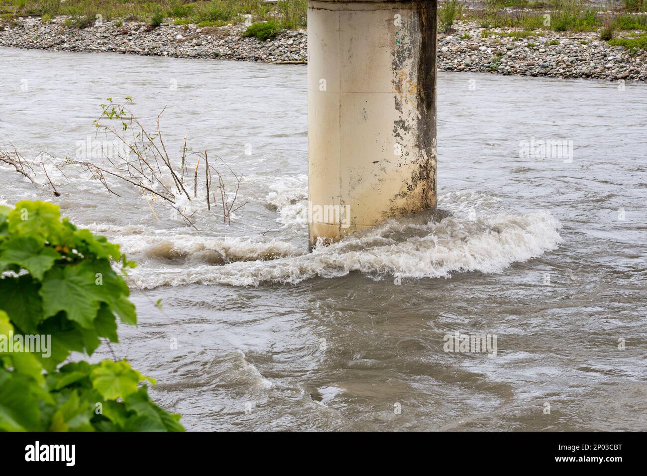 A raging river and tree branches stuck at the bridge support after heavy rains and a hurricane ...