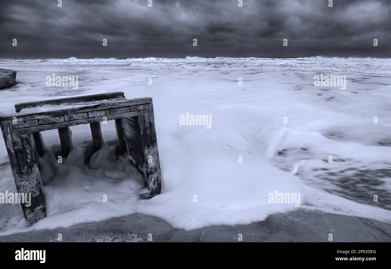 A wooden trash crate floats in the surf during high tide at ...