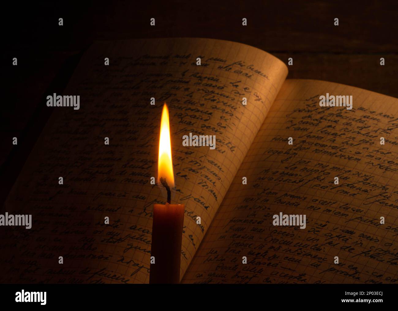 Burning candle on an open book in dark room with copy space. reading a ...