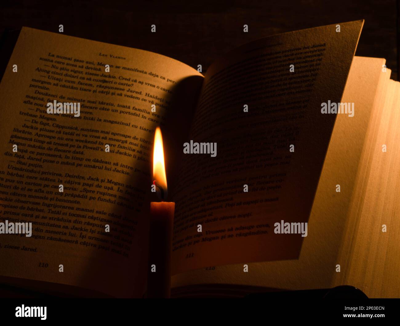 Burning candle on an open book in dark room with copy space. reading a ...