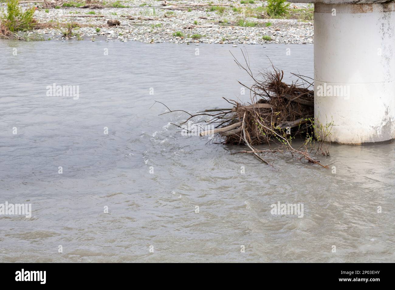 A raging river and tree branches stuck at the bridge support after heavy rains and a hurricane ...