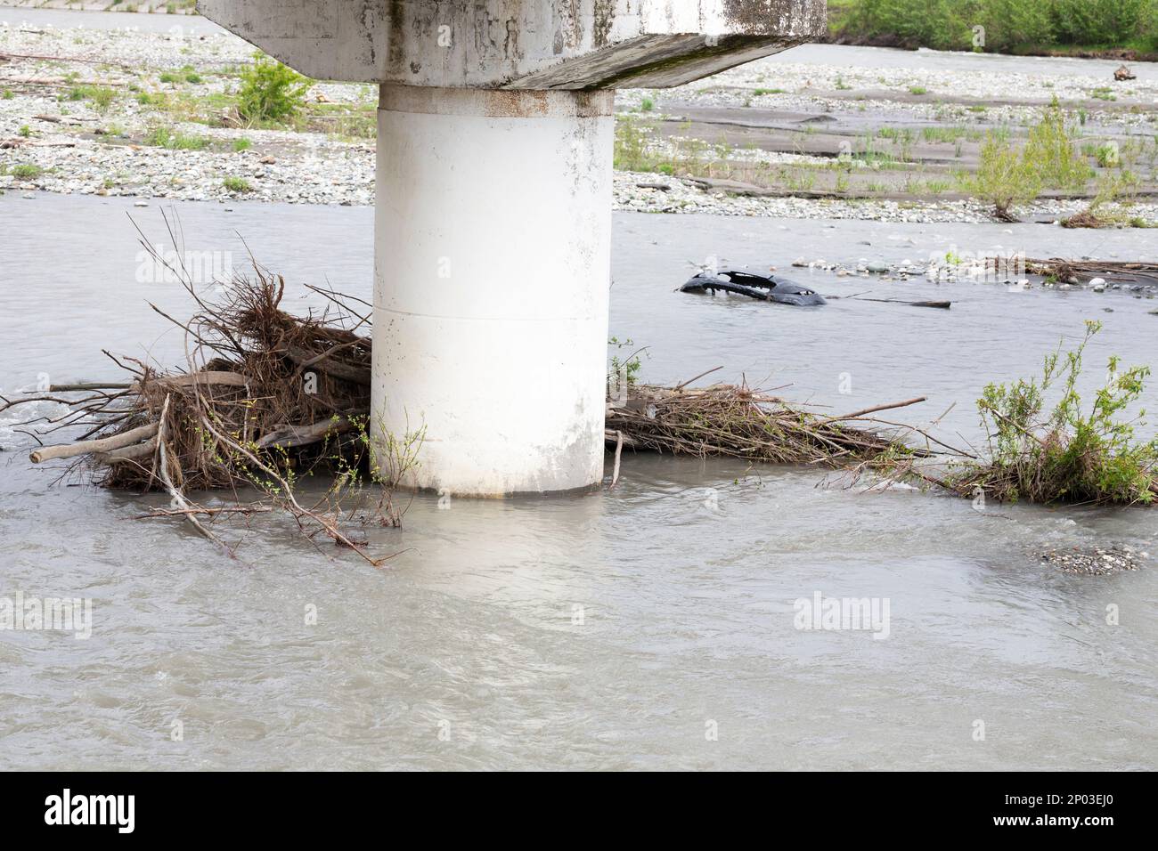 A raging river and tree branches stuck at the bridge support after heavy rains and a hurricane ...