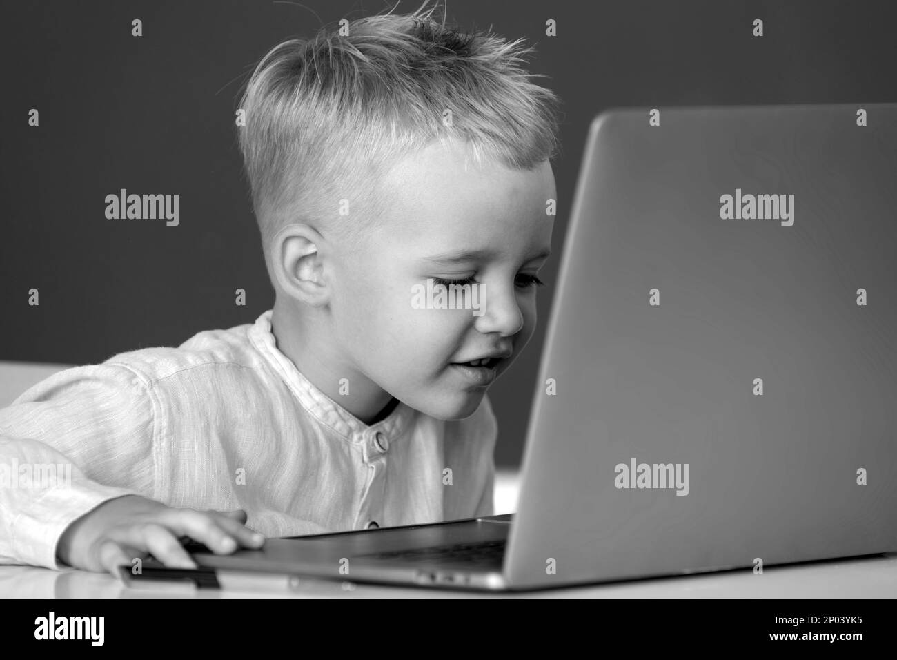 Little student boy using laptop computer in school class. Funny blonde ...