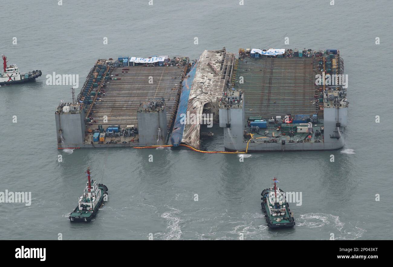 The partially lifted sunken ferry Sewol, center, is ready for transport ...