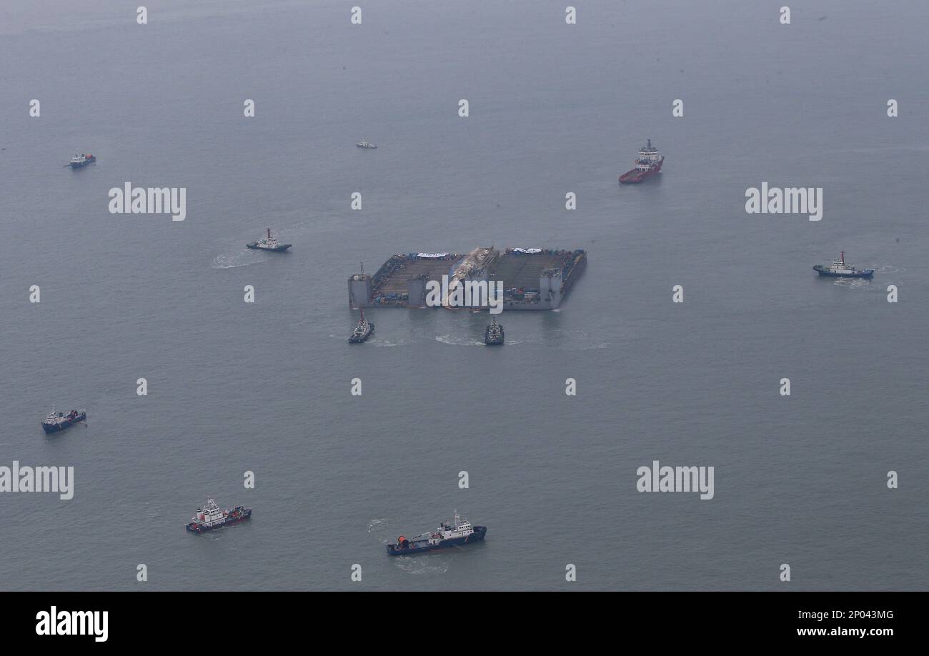 The partially lifted sunken ferry Sewol, center, between two barges, is ...