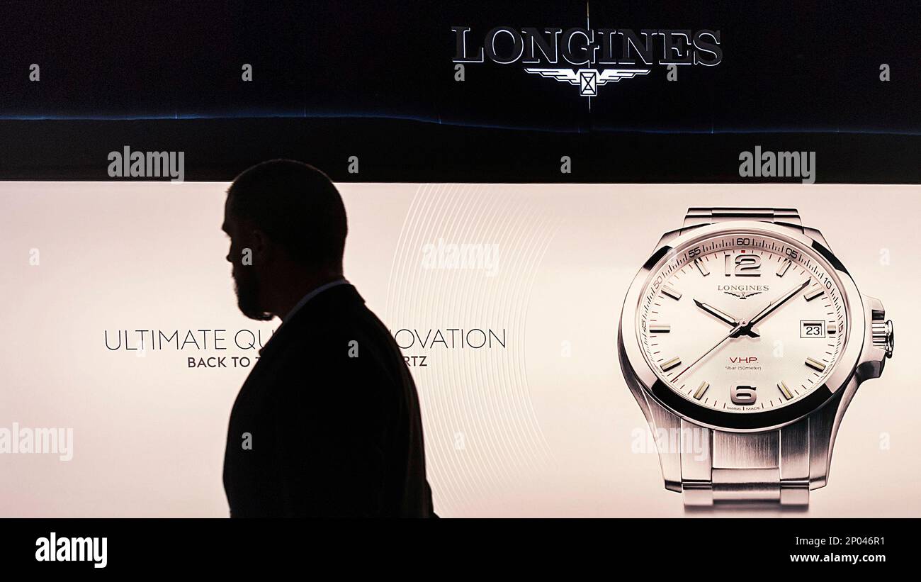 A visitor walks past the Longines booth at the world watch and ...
