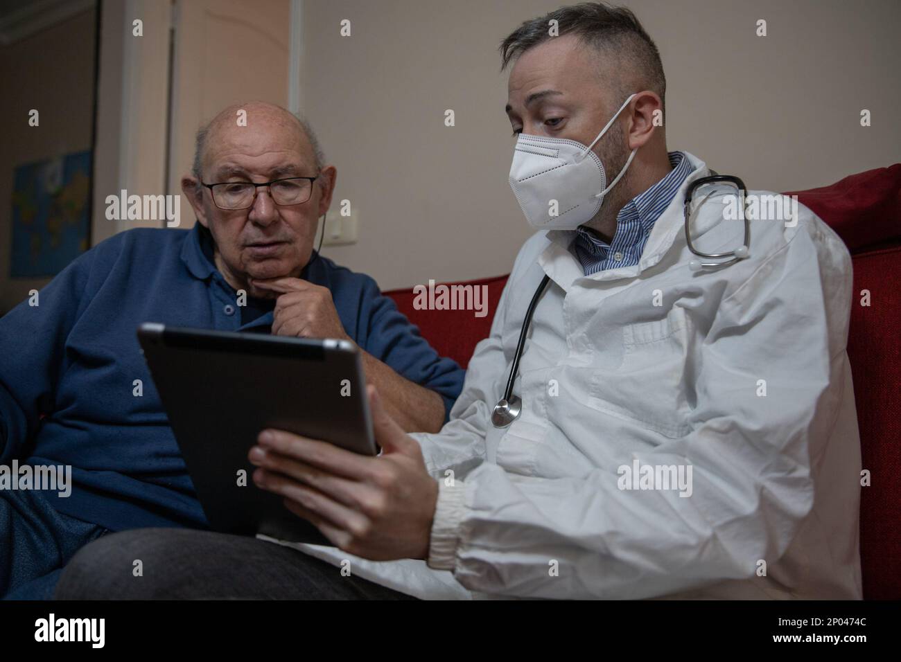 A general practitioner during a home visit to his elderly patient Stock ...
