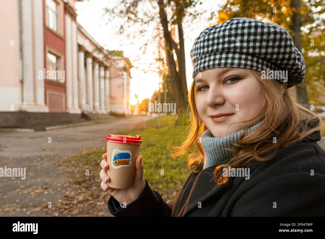 Ukraine. Sunset. City Park. Girl sits on a bench and holds cup of ...
