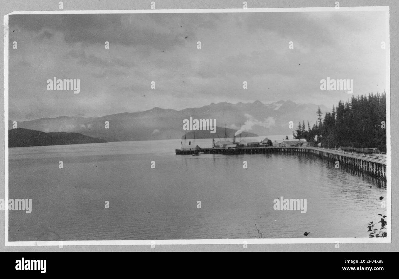 Railroad trestle with loading dock jutting into bay; snow-capped ...