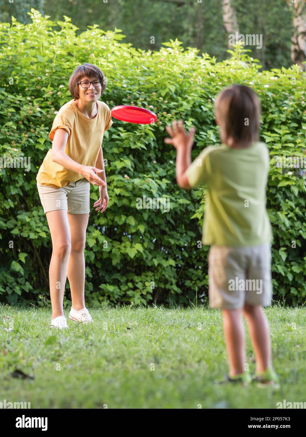 Mother and son play frisbee on grass lawn. Summer vibes. Outdoor ...