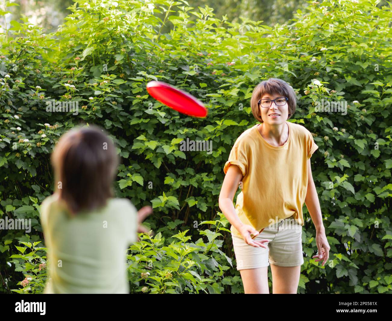 Mother and son play frisbee on grass lawn. Summer vibes. Outdoor ...