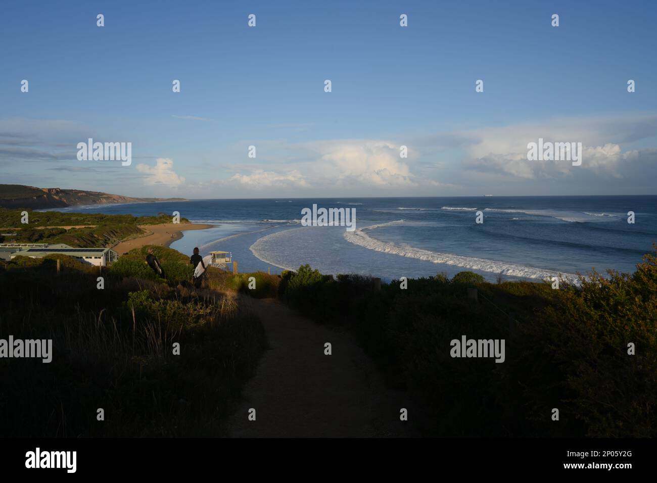 Two surfers survey the evening surf at Anglesea and the view of the ...