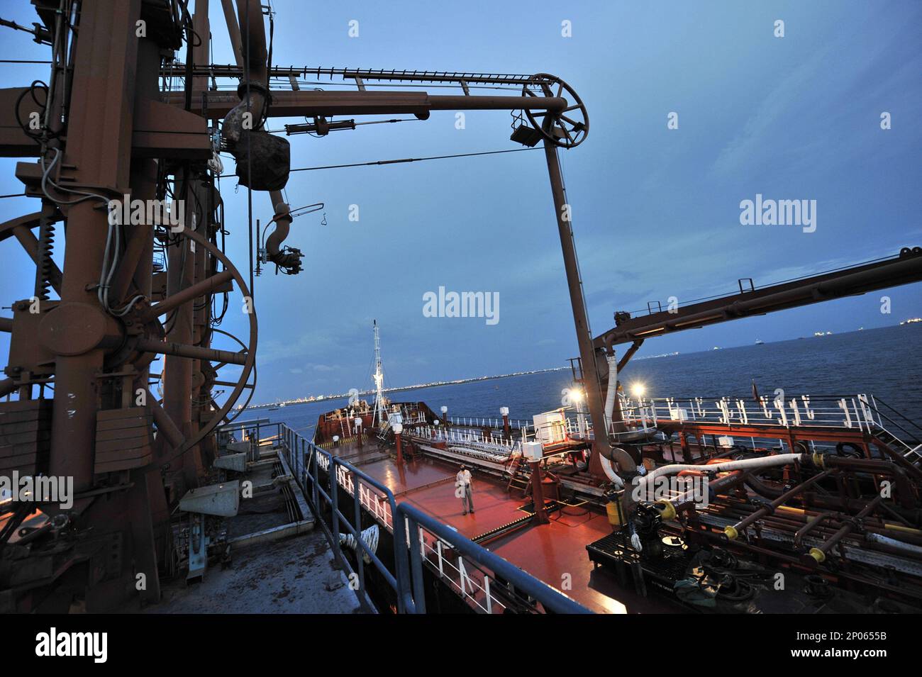 Docked at a remote pier in western Singapore, a small tanker unloads ...