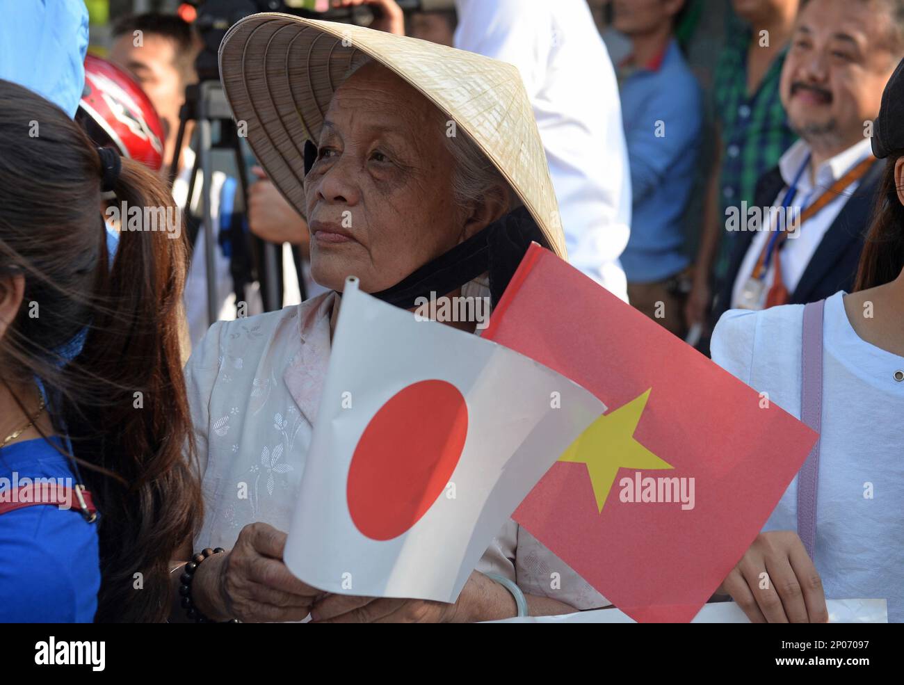 A Vietnamese woman holds Vietnamese and Japanese flags as she watches ...