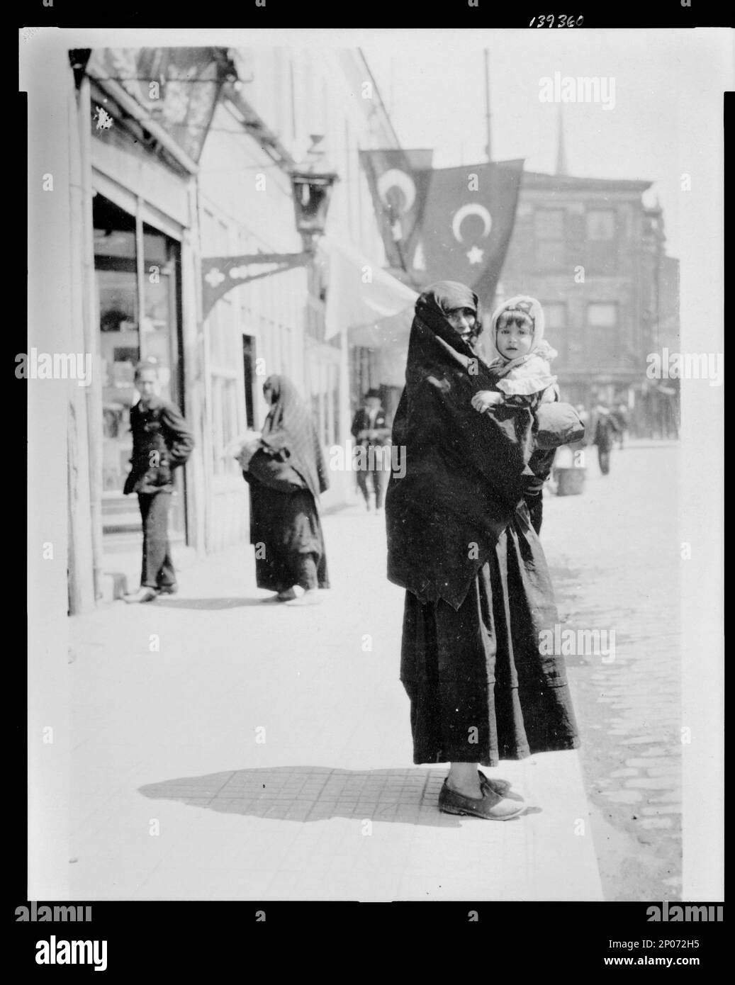 Woman holding a baby on a street in Istanbul. Title devised by Library staff, Frank and Frances ...