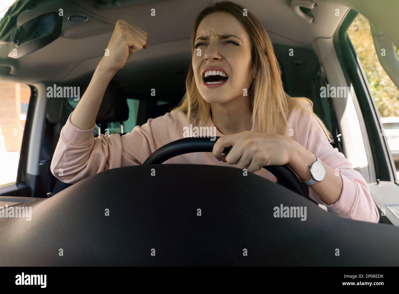 Stressed angry woman in driver's seat of modern car, view through ...