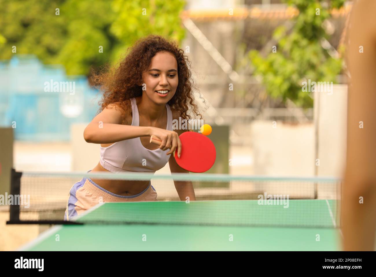 African-American woman playing ping pong with friend outdoors Stock ...