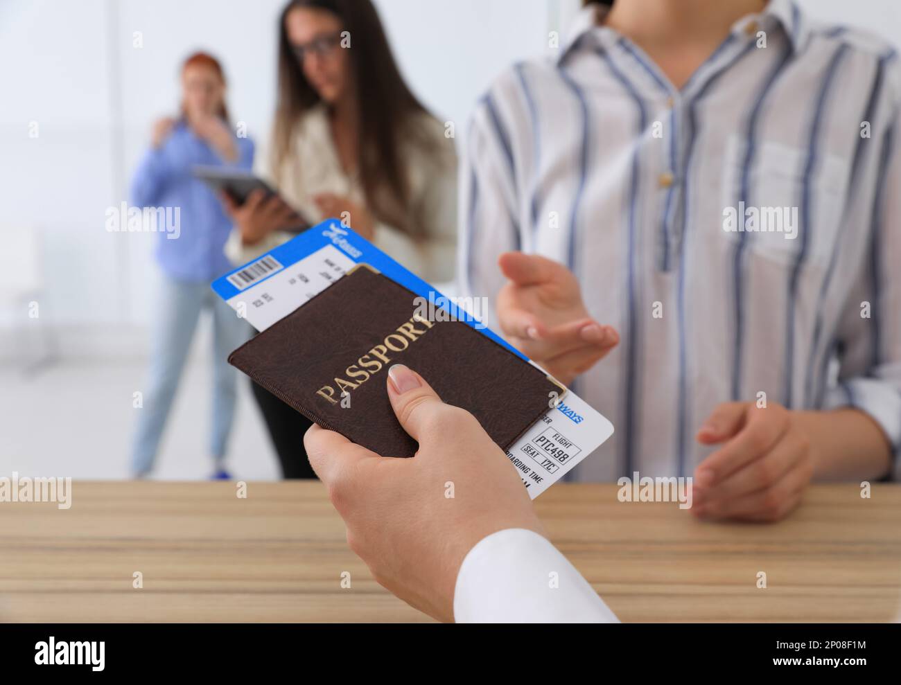 Agent giving passport with ticket to client at check-in desk in airport ...