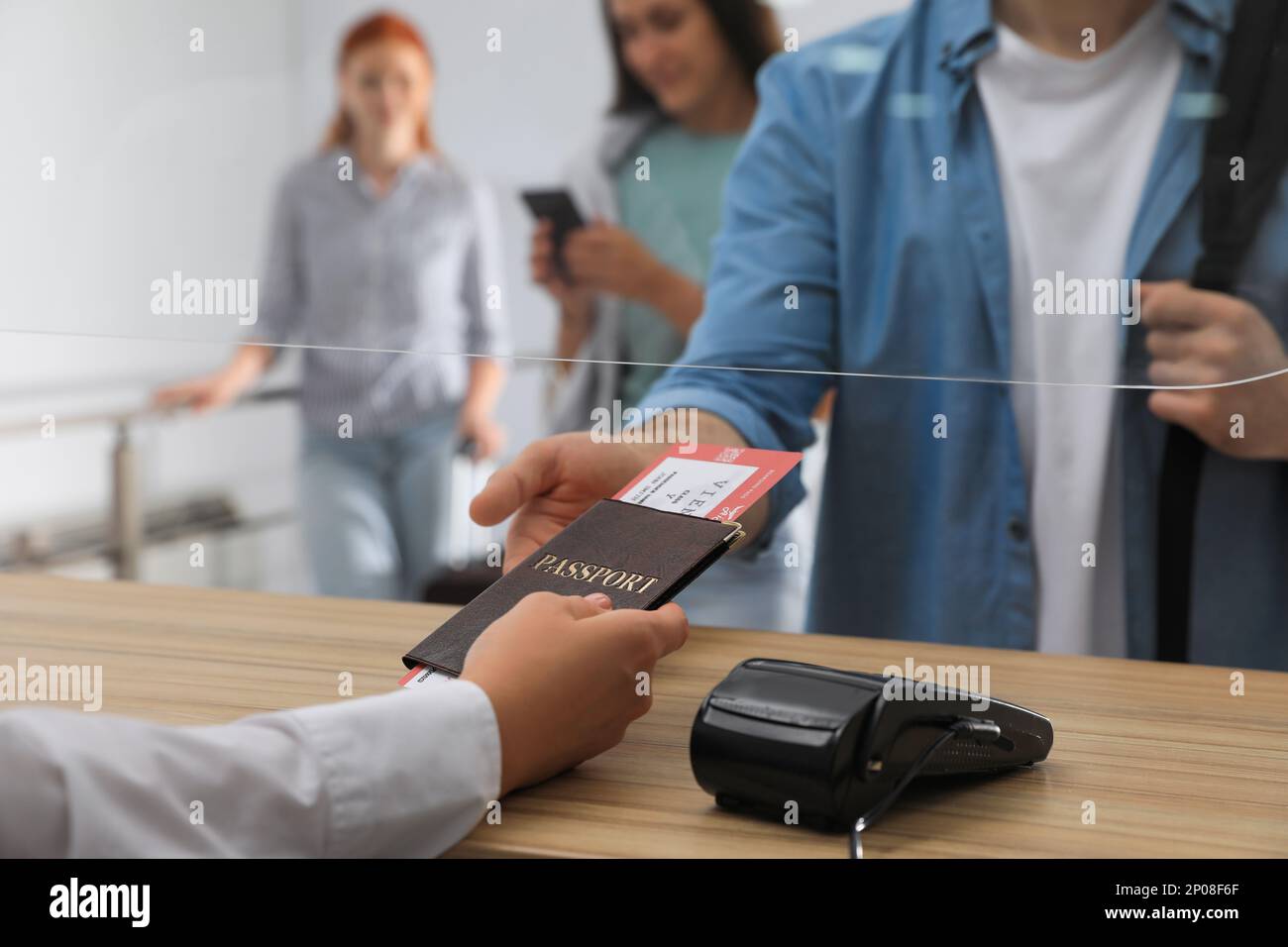 Agent giving passport with ticket to client at check-in desk in airport ...