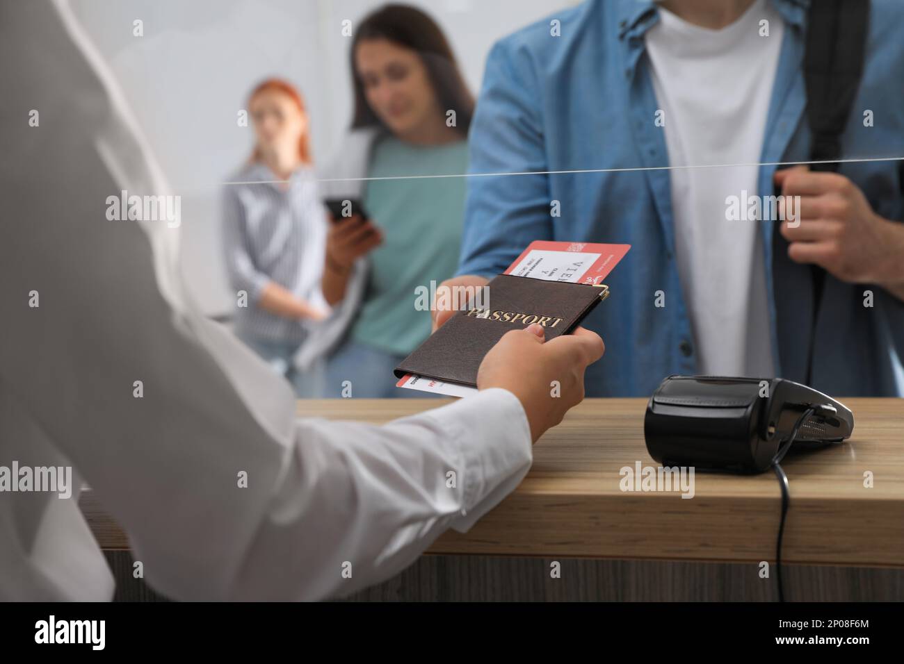 Agent giving passport with ticket to client at check-in desk in airport ...