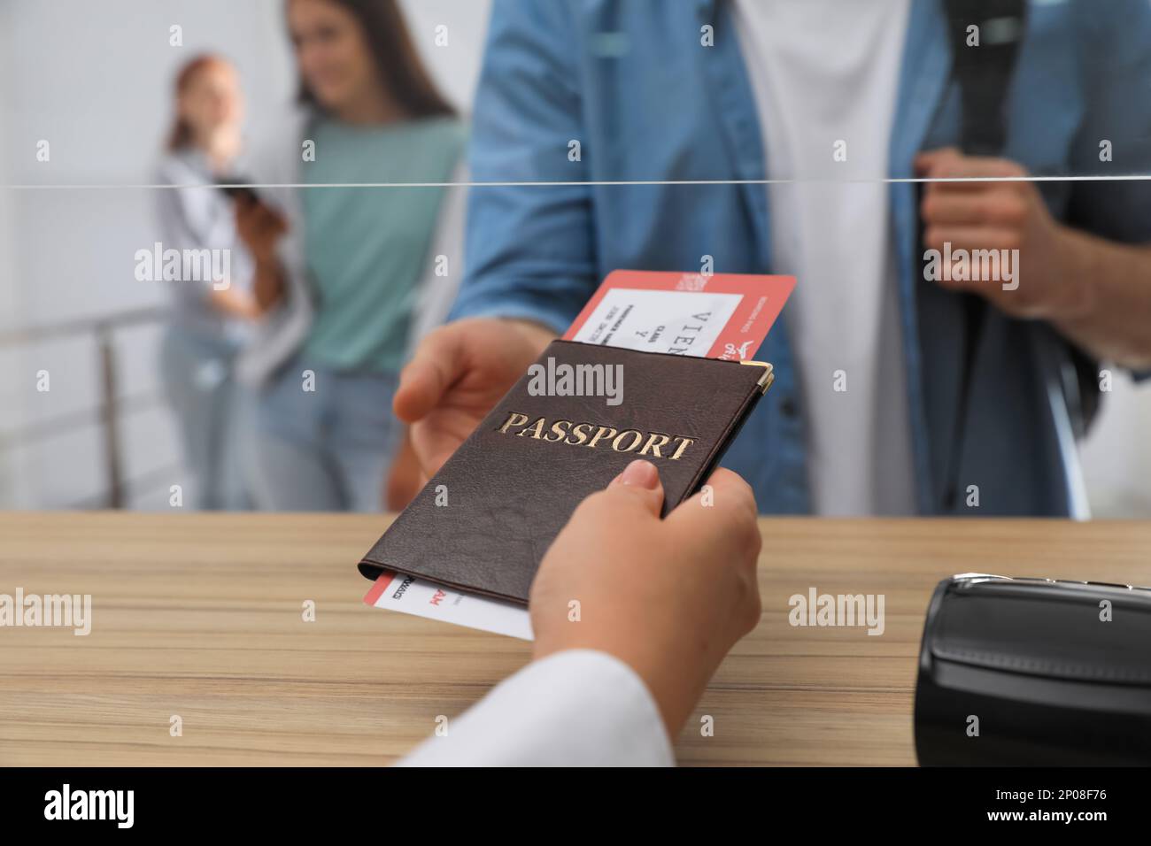 Agent giving passport with ticket to client at check-in desk in airport ...